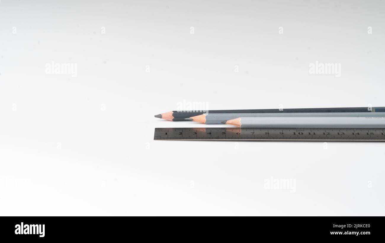 Wooden simple pencils and a metal ruler horizontally on a white ...