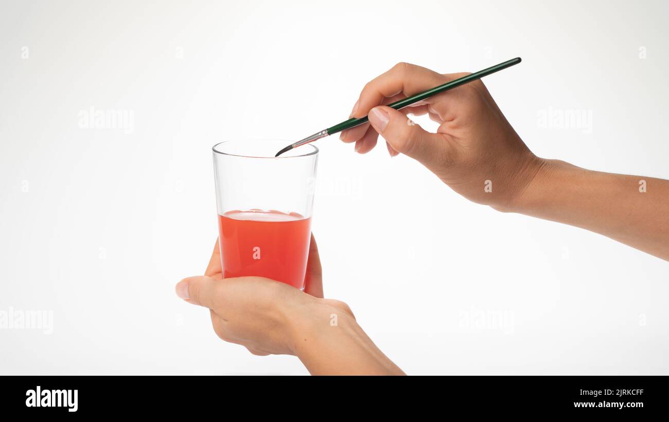 Dip a brush in a glass of water drawing, women's hands on a white ...
