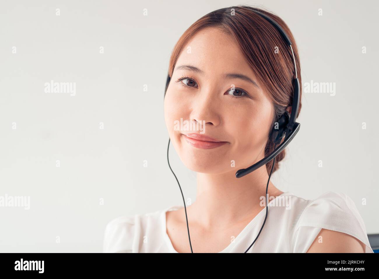 Portrait of happy Vietnamese technical support worker wearing headset ...