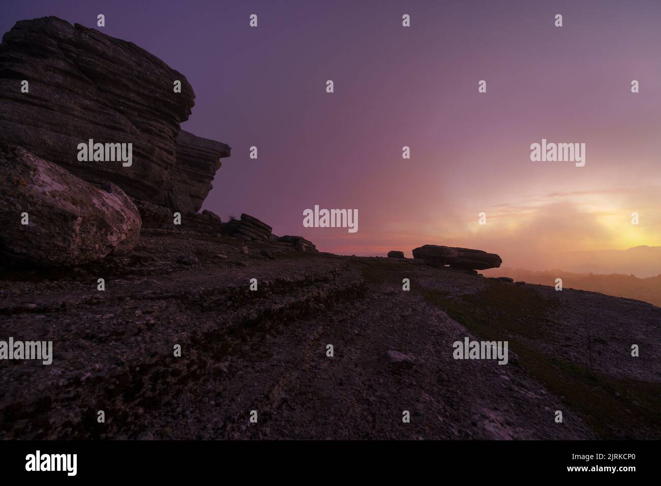 Landscape at sunrise over some rocky mountains under a sky with low ...