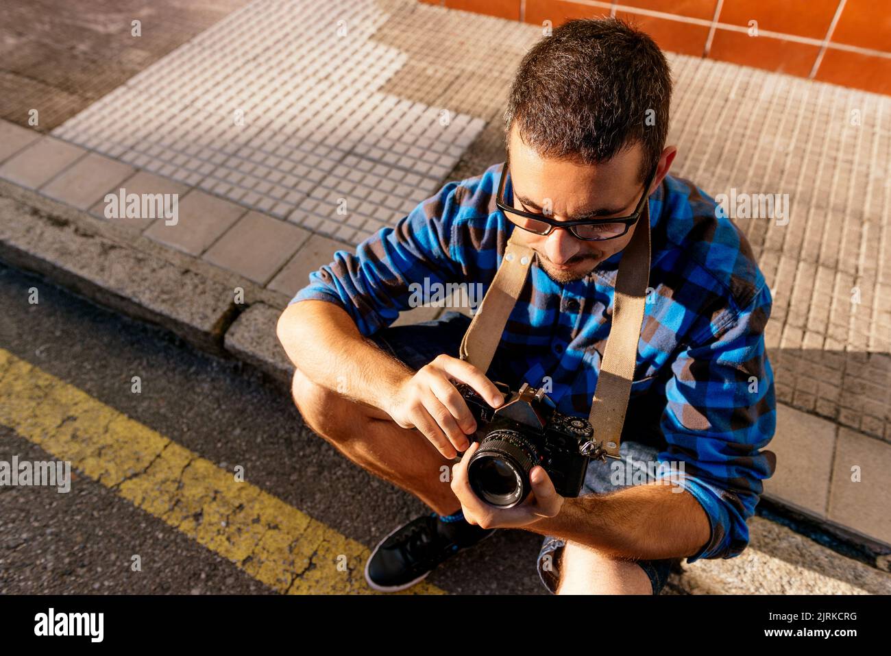 From above young charismatic male photographer in casual clothes ...