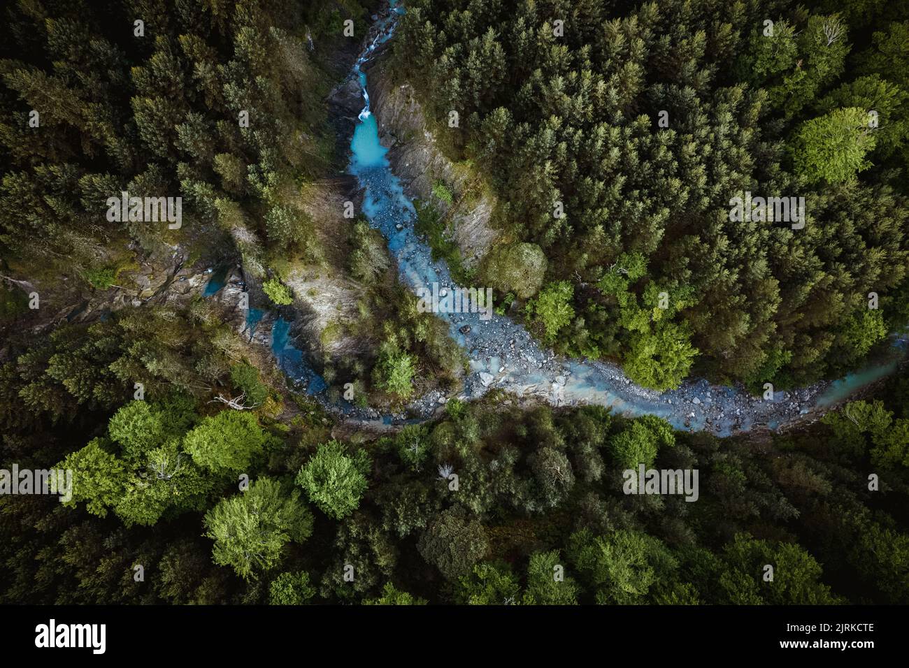 Drone view of narrow brook flowing through dense woodland with lush ...