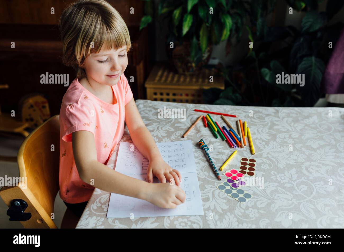 Cute little girl doing homework besides a window Stock Photo - Alamy
