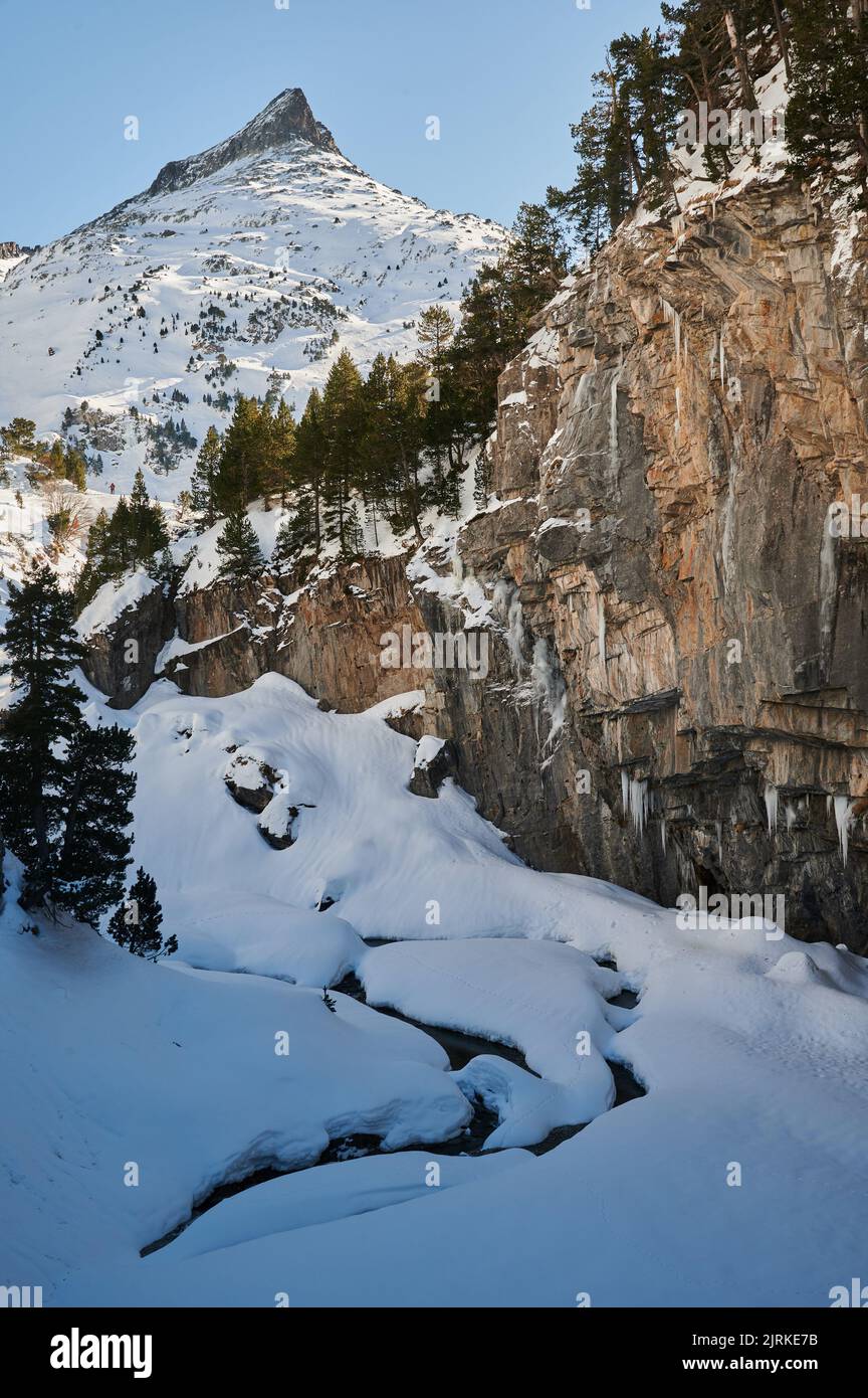 Clear frozen brook flowing on rocky formation covered with snow in ...
