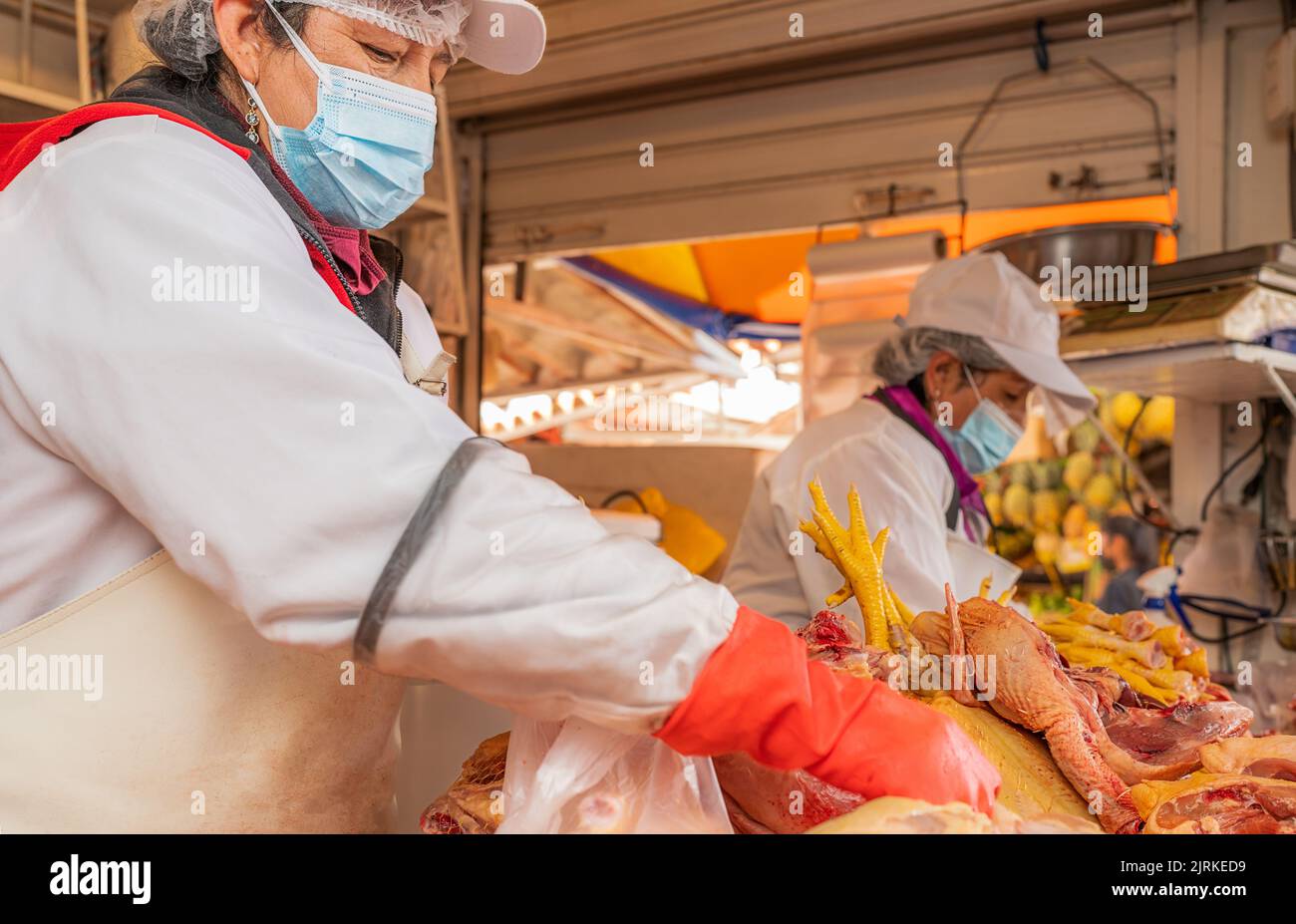 Peruvian female sellers in face masks and aprons standing behind ...