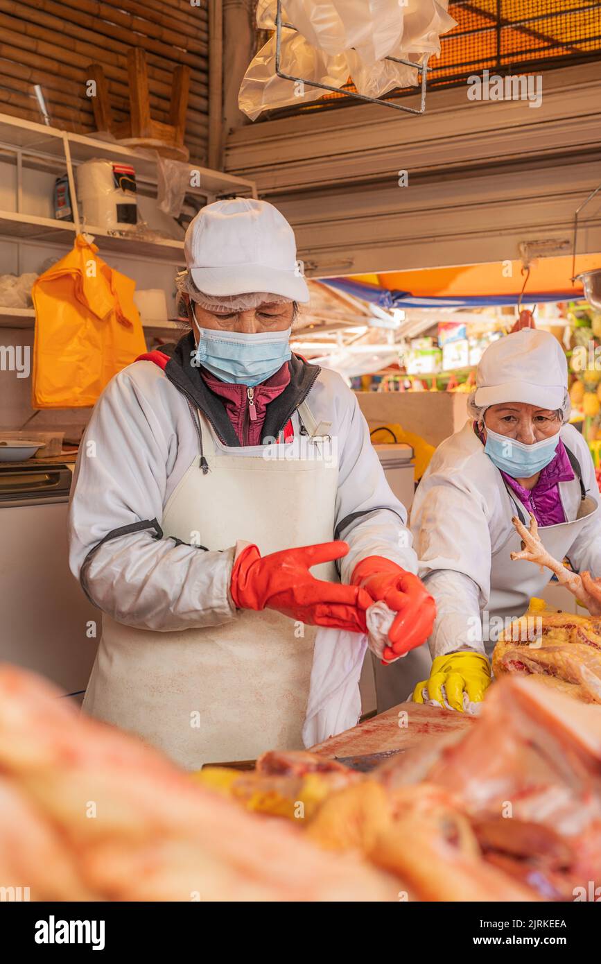 Peruvian female sellers in face masks and aprons standing behind ...