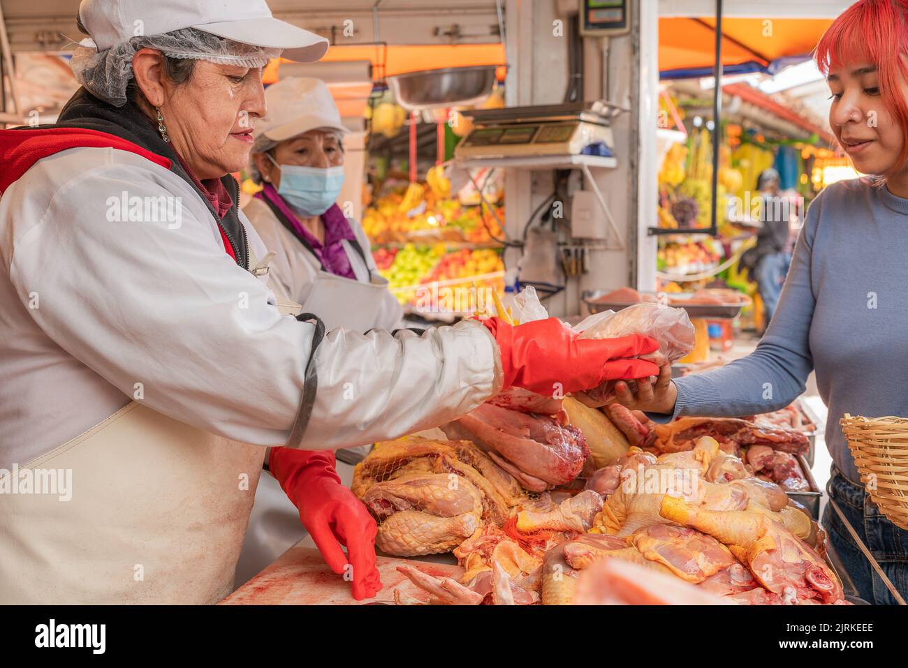 Side view of customer standing near Peruvian female workers in aprons ...