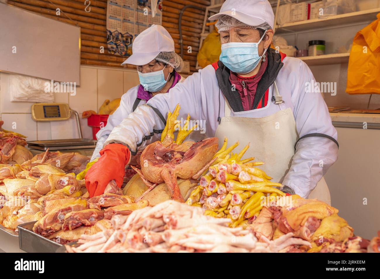 Peruvian female sellers in face masks and aprons standing behind ...
