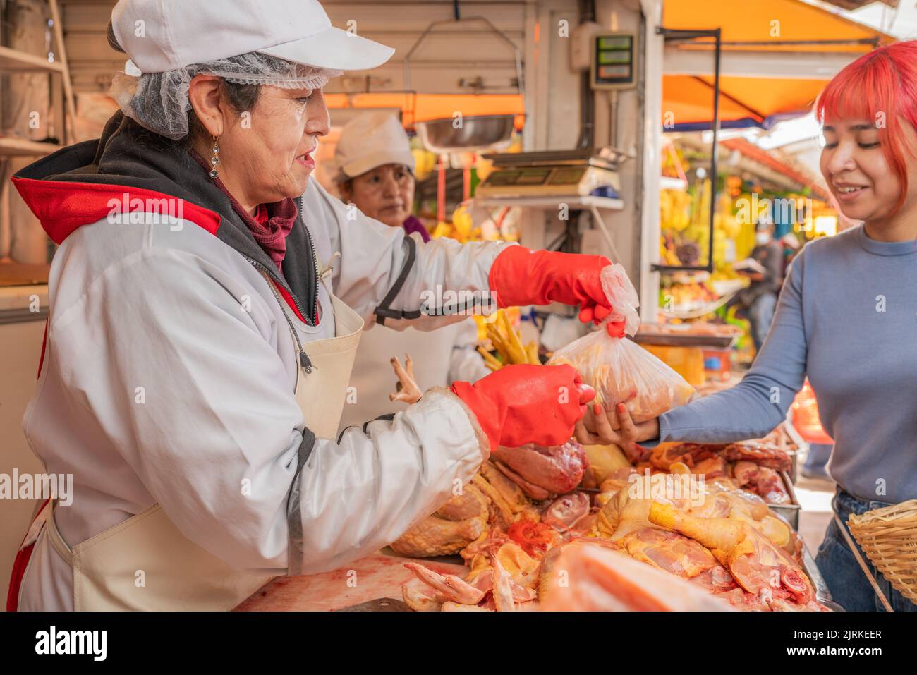 Side view of customer standing near Peruvian female workers in aprons ...