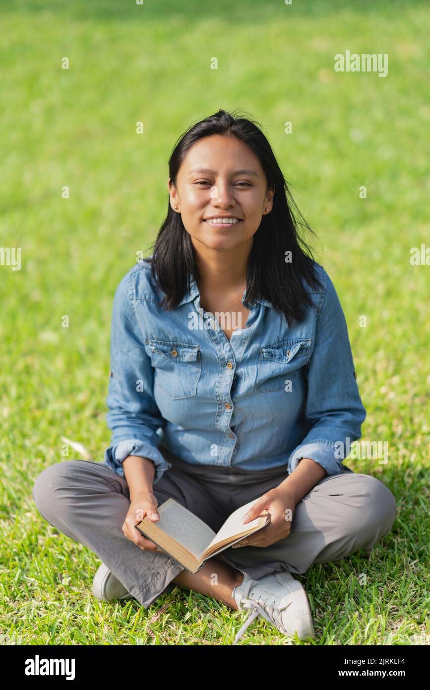 Full body of optimistic female sitting with crossed legs and reading ...
