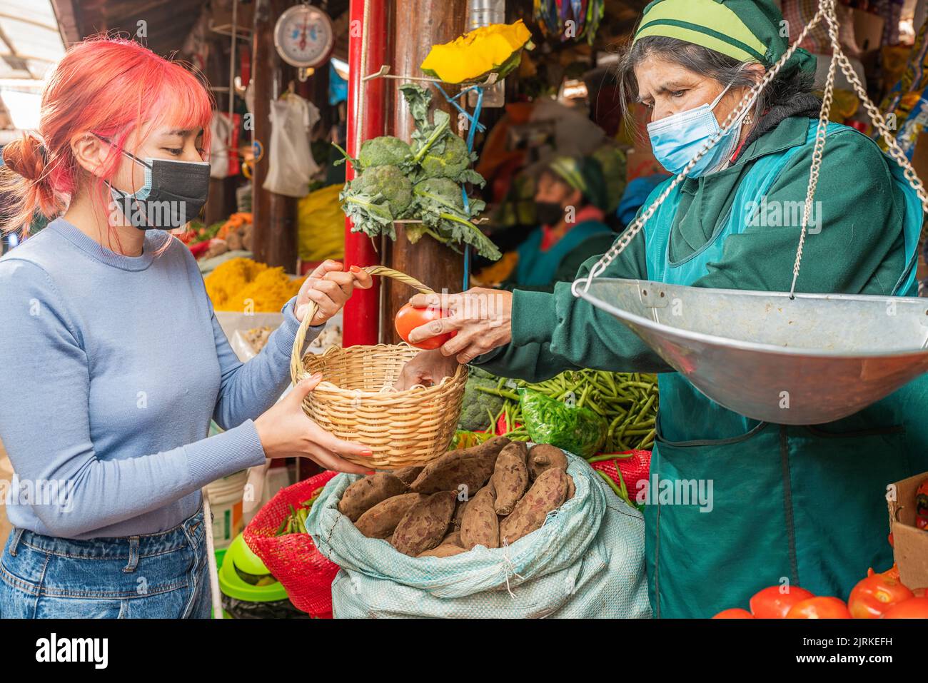 Crop Peruvian female seller in face medial mask selling ripe green ...