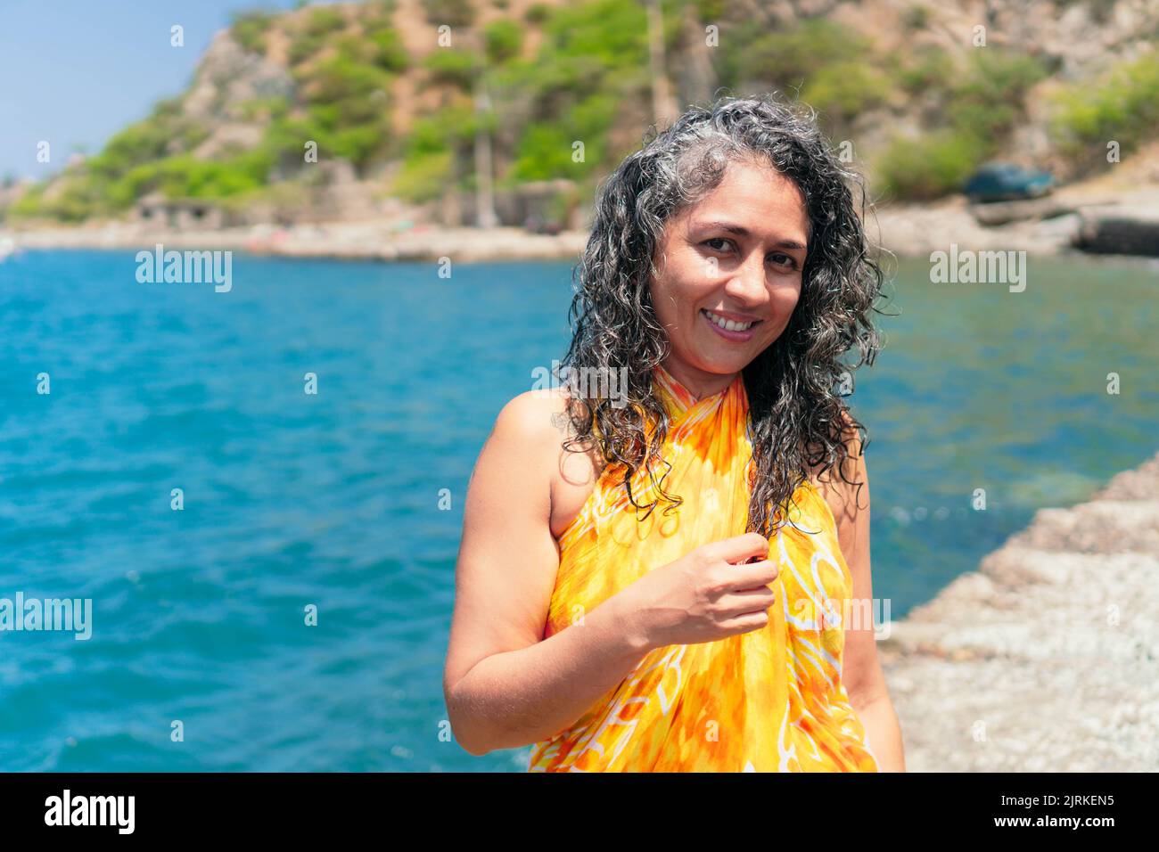 Dreamy mature ethnic female tourist in colorful pareo with curly gray ...