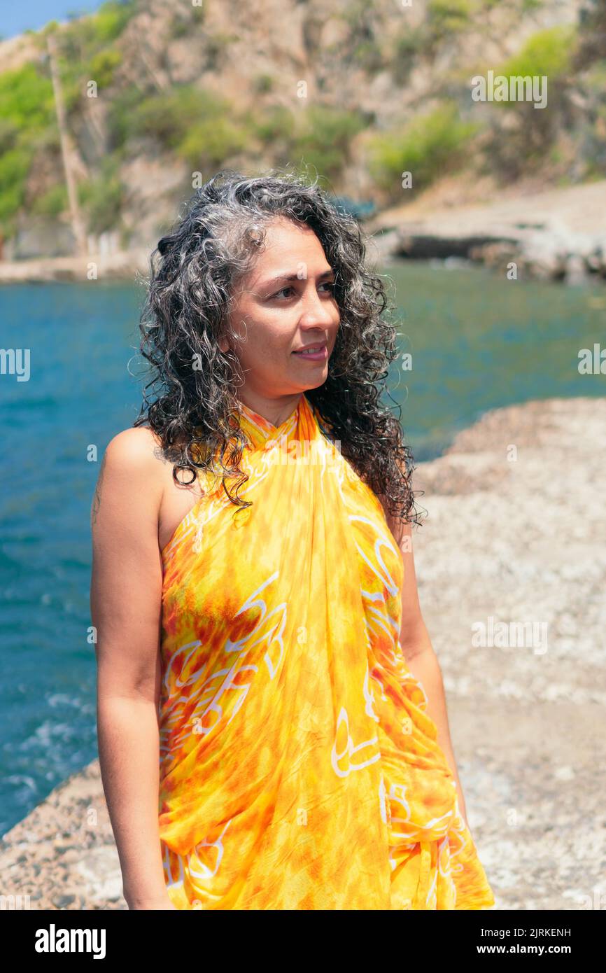 Dreamy mature ethnic female tourist in colorful pareo with curly gray ...