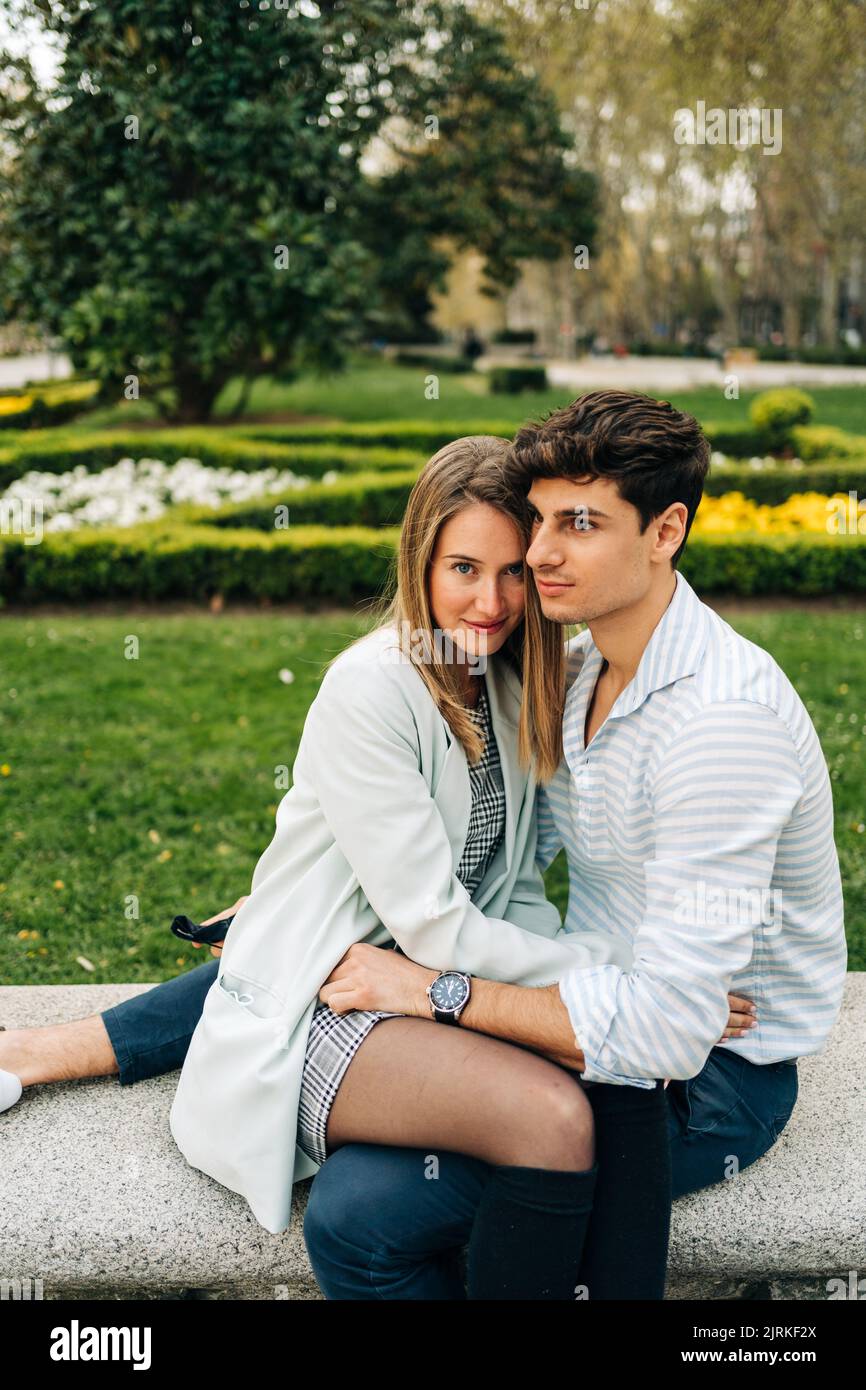 Side view of gentle couple hugging tenderly while sitting in urban ...