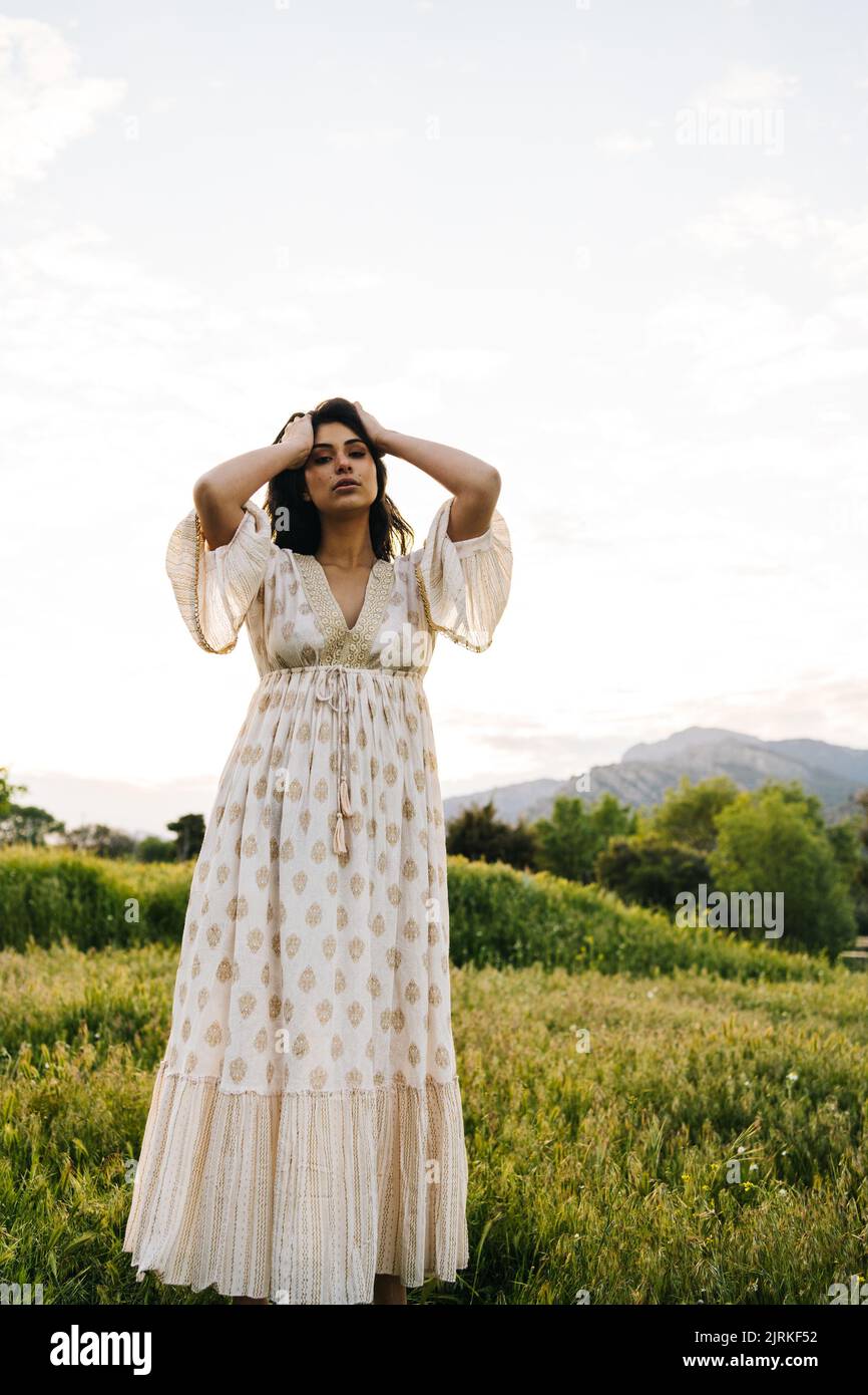 Full body of serious young ethnic female traveler in boho style maxi ...