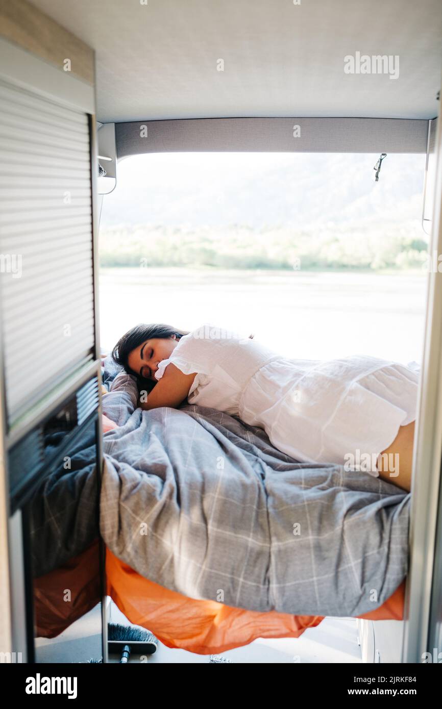 Side view of peaceful Hispanic female traveler sleeping on soft bed in ...