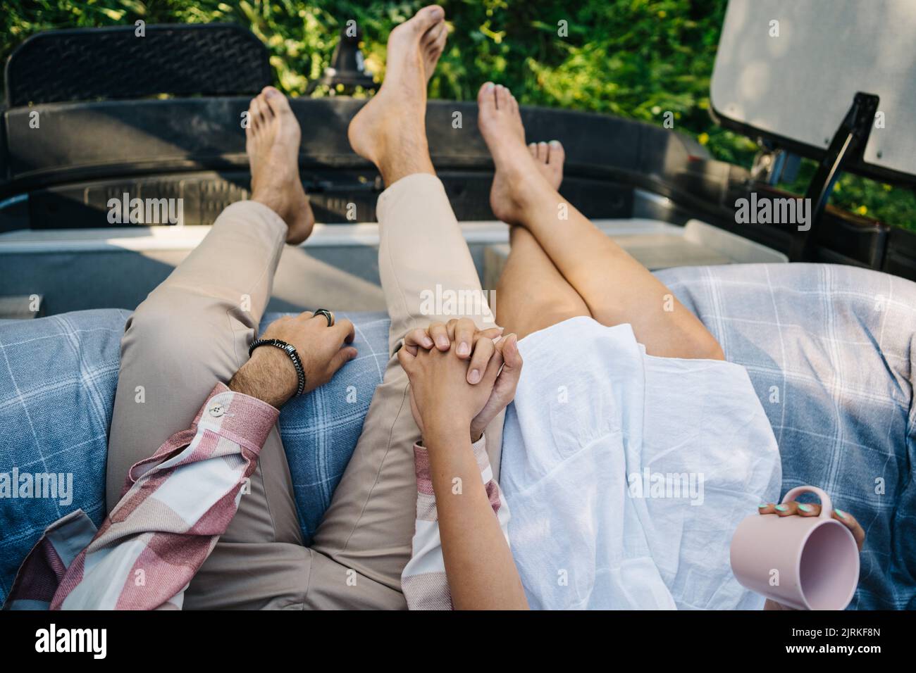 From above of crop barefoot legs of unrecognizable couple of travelers ...