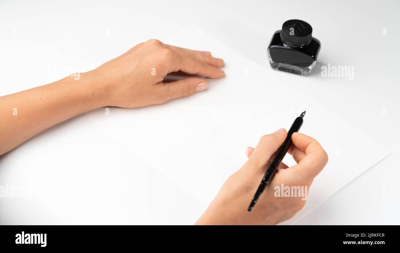 A woman's hands hold a fountain pen on a white background with ...
