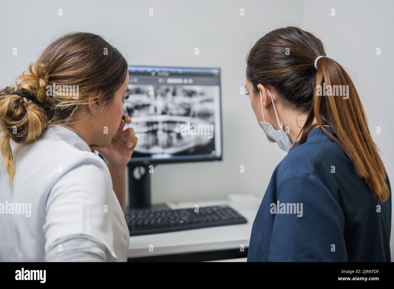 Back view of women in medical uniform discussing teeth X ray on ...