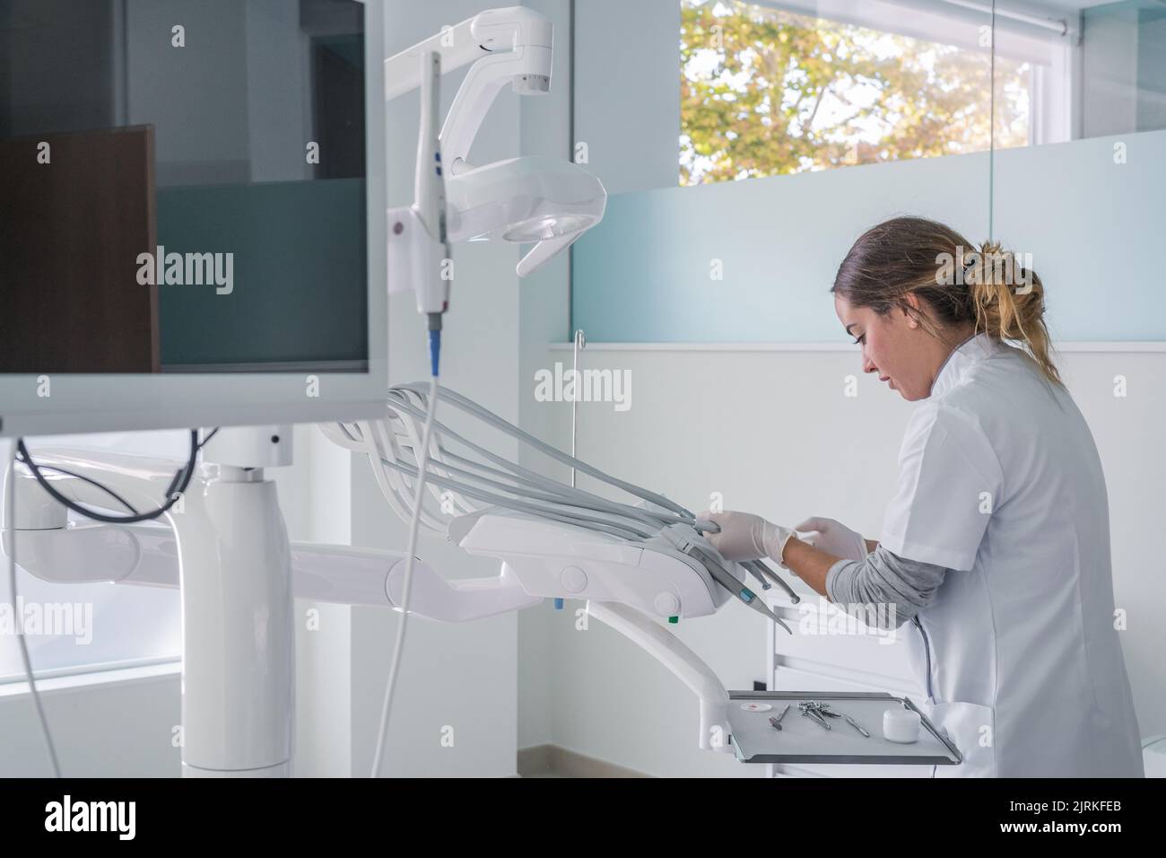 Side view of woman in medical uniform adjusting tools settings while ...