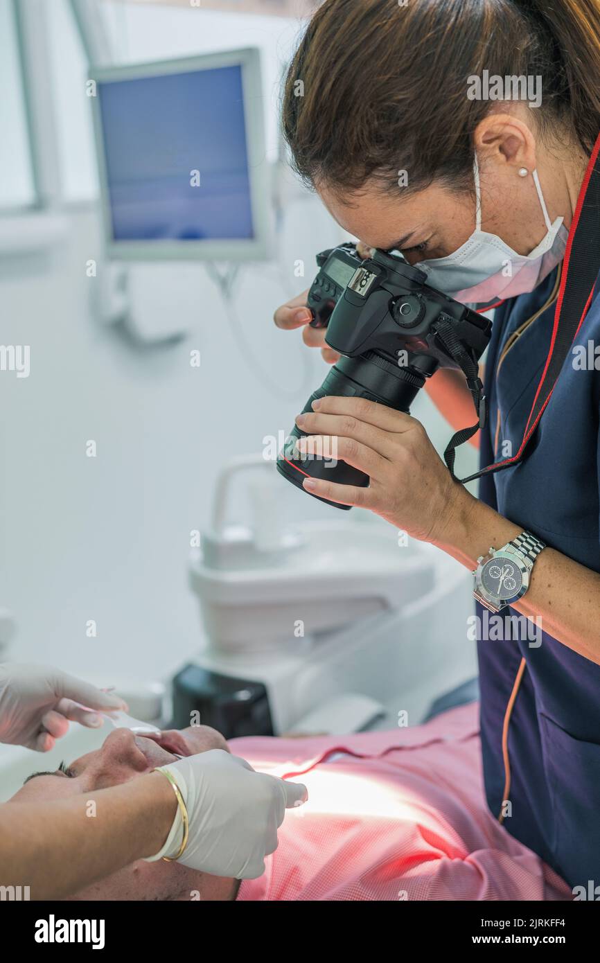 Female doctor taking photos of man teeth during checkup procedure in ...