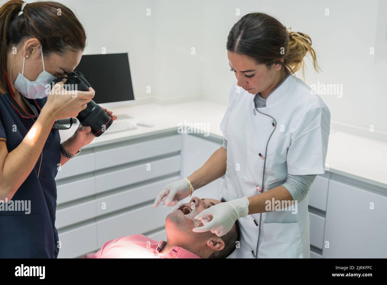 Female doctor taking photos of man teeth during checkup procedure in ...