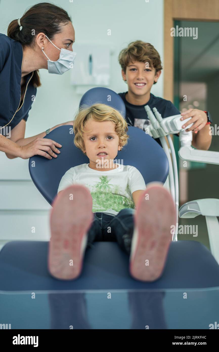 Friendly boy smiling and comforting little brother during visit in ...