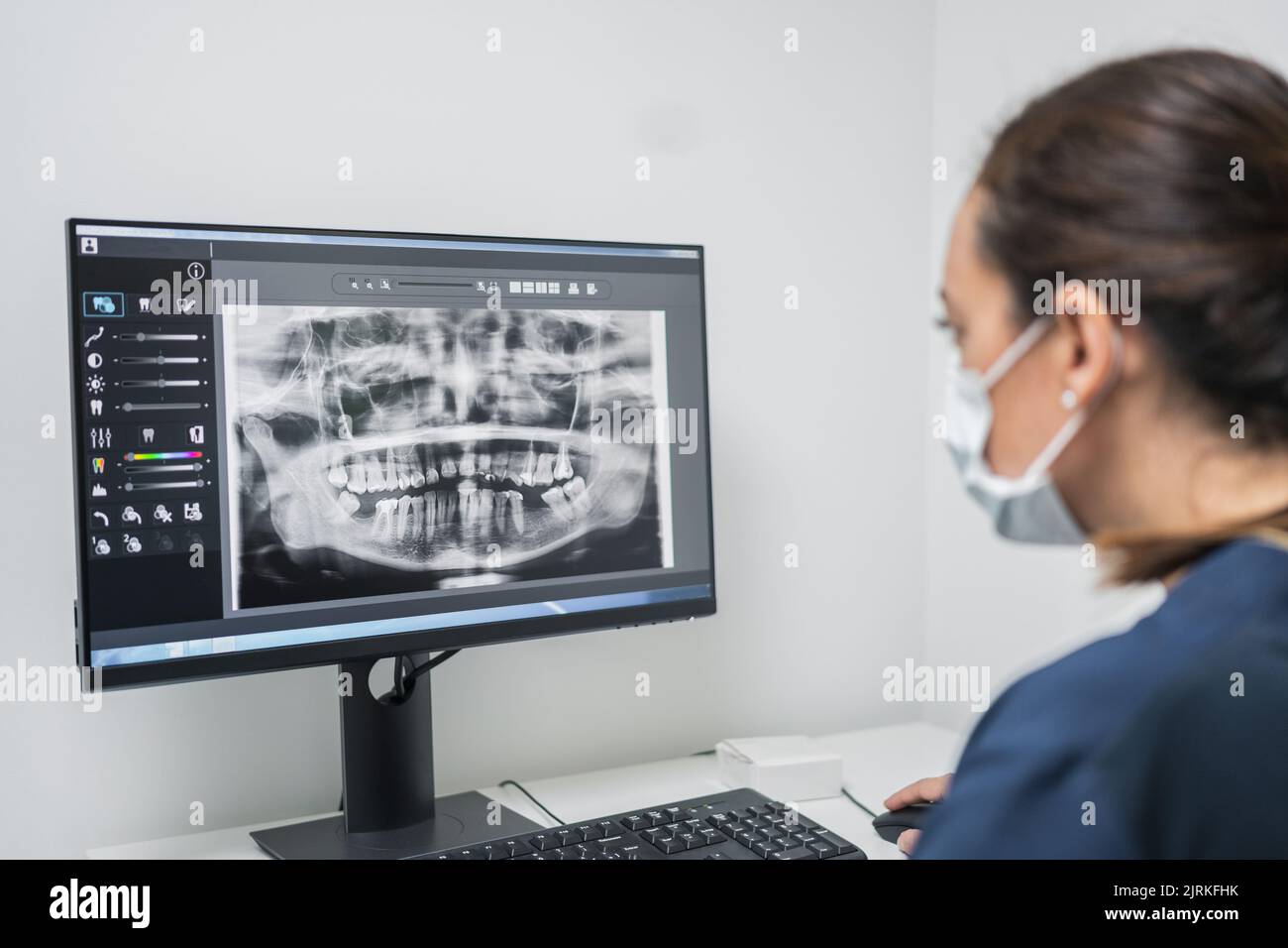Back view of woman in medical uniform looking at teeth X ray on ...