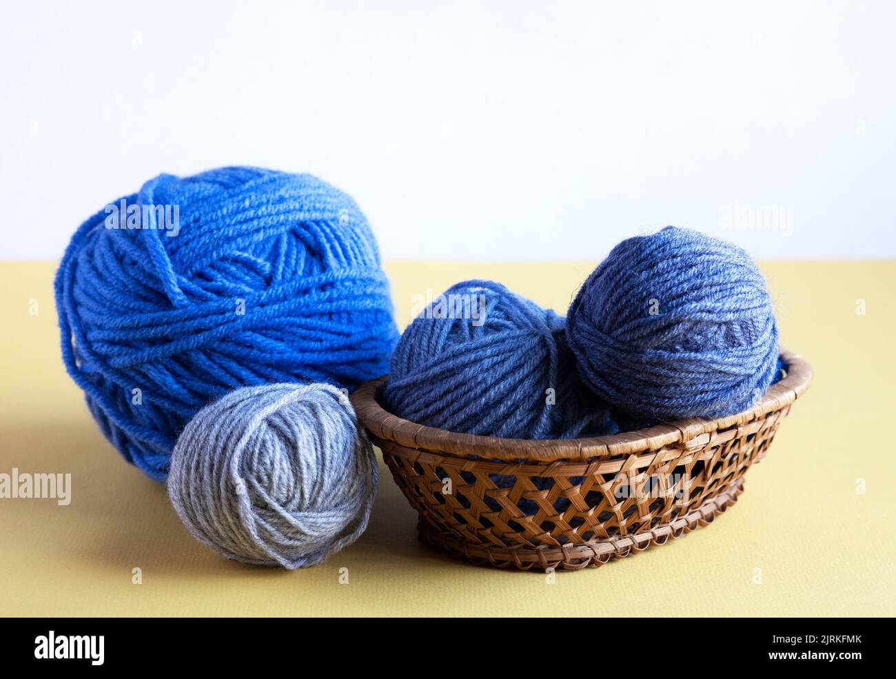 Blue balls of knitting threads on a yellow background in a basket Stock ...