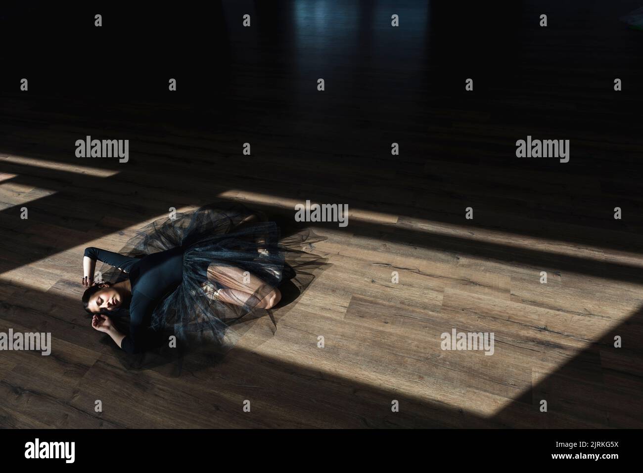 Elegant ballerina on black dress laying on dance studio floor with ...