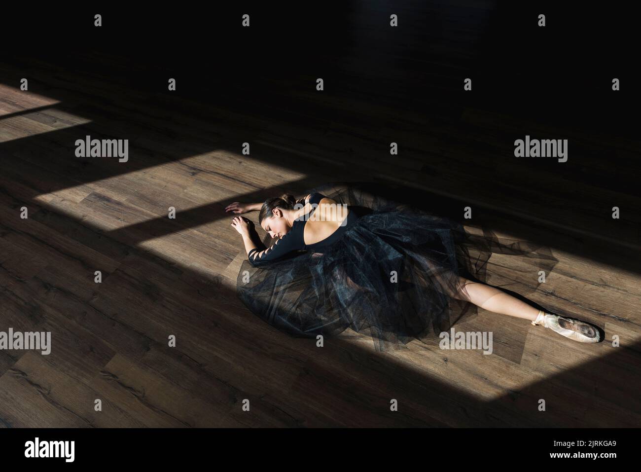 Elegant ballerina on black dress laying on dance studio floor with ...