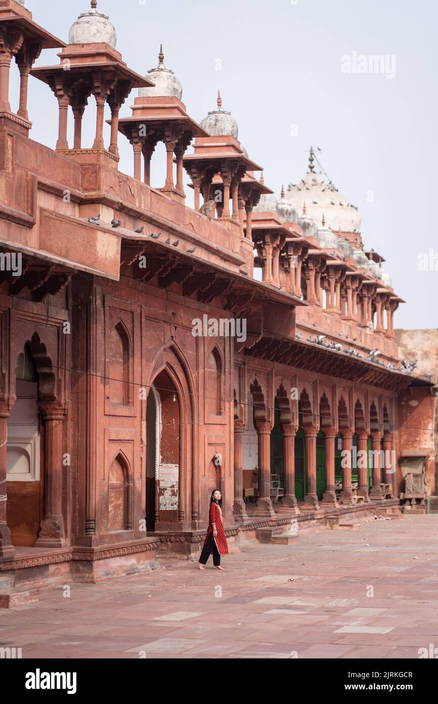 Side view of ethnic woman walking barefoot in weathered courtyard of ...