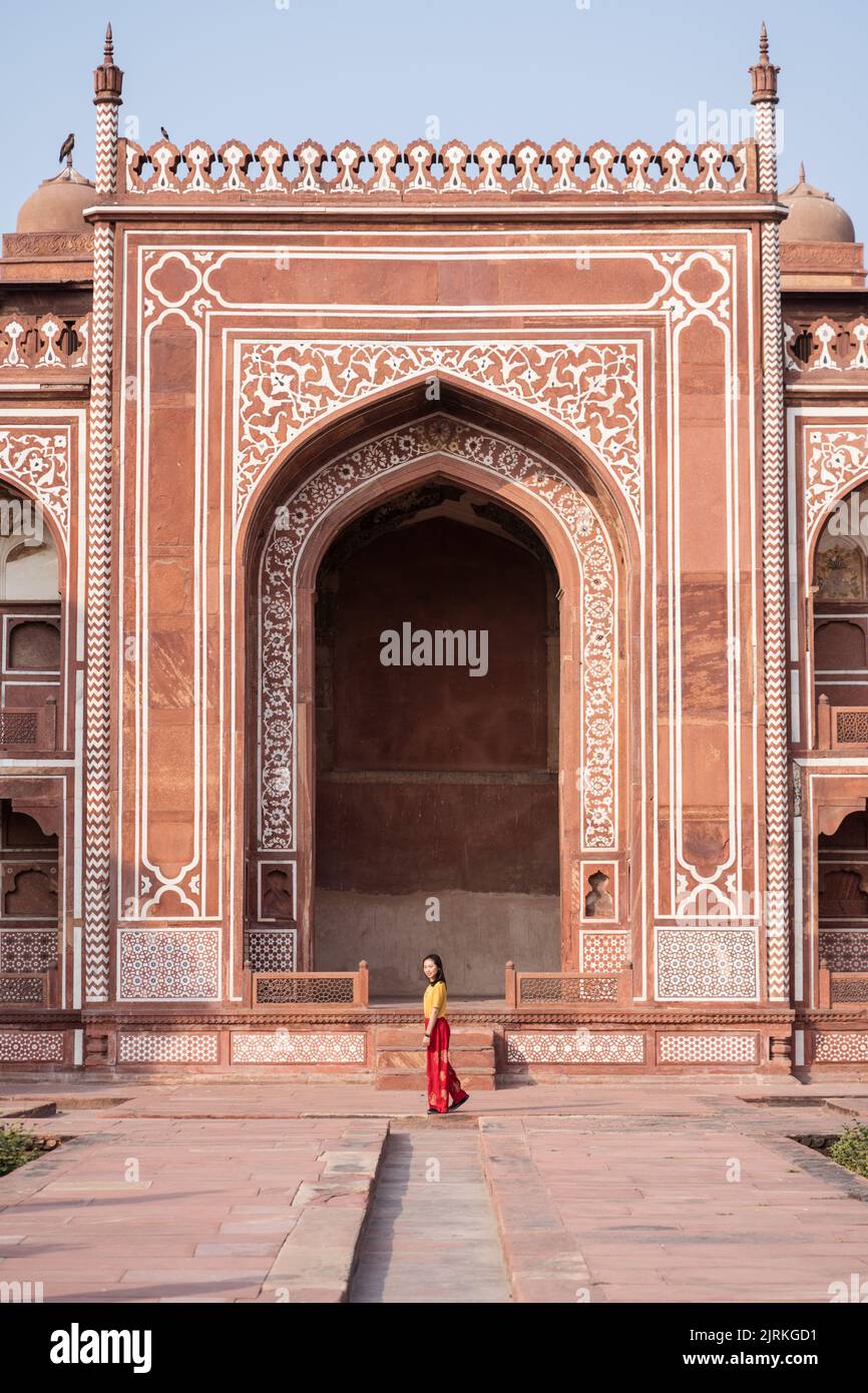 Full length woman in colorful outfit standing against ornamental arch ...
