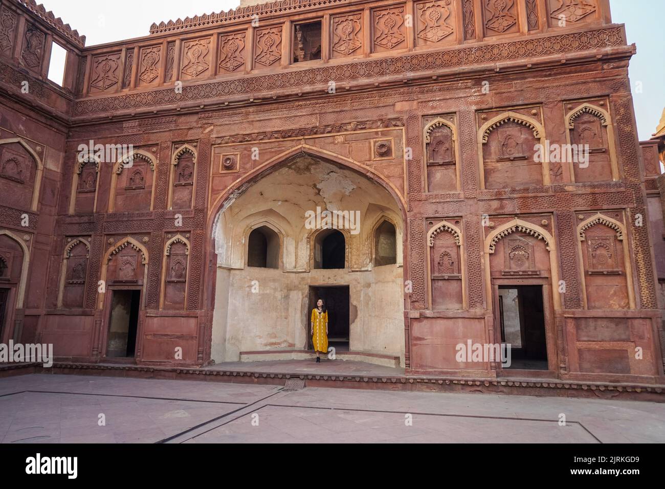 Full body woman in yellow dress standing in arch of aged Agra Fort in ...