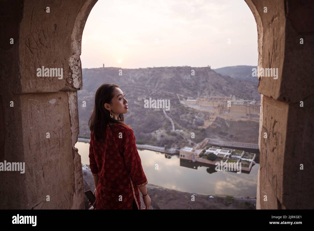 Side view of Asian woman looking away standing in a ancient arch while ...