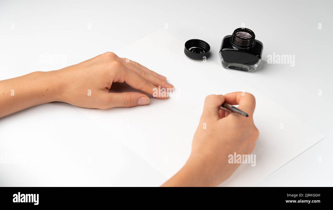 A woman's hands hold a fountain pen on a white background with ...