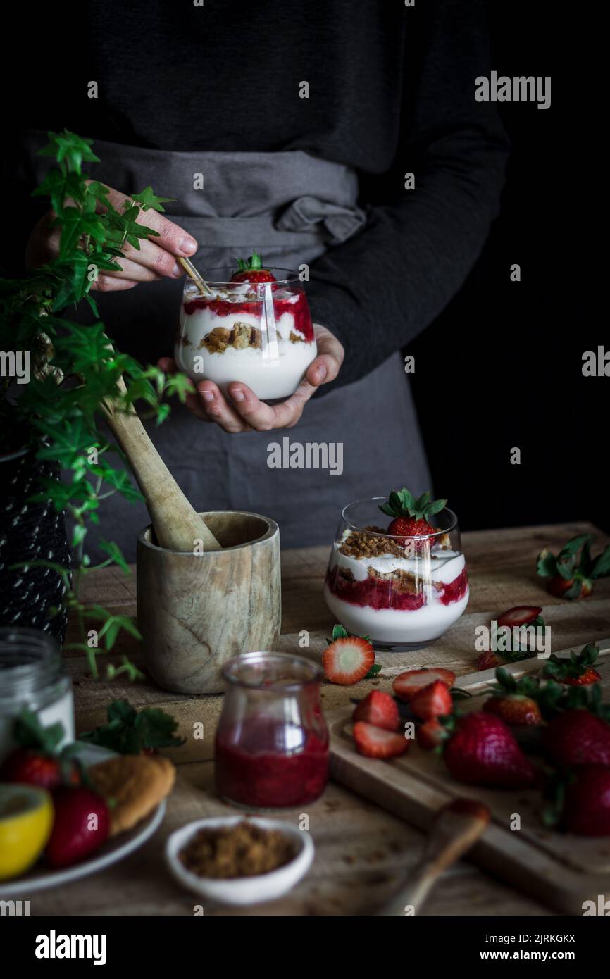 Crop person in black shirt and gray apron cooking delicious dessert ...