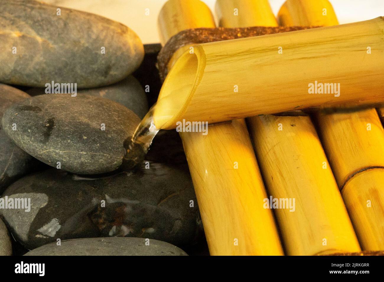 A close-up of yellow bamboo sticks on rocks, a bamboo water fountain ...
