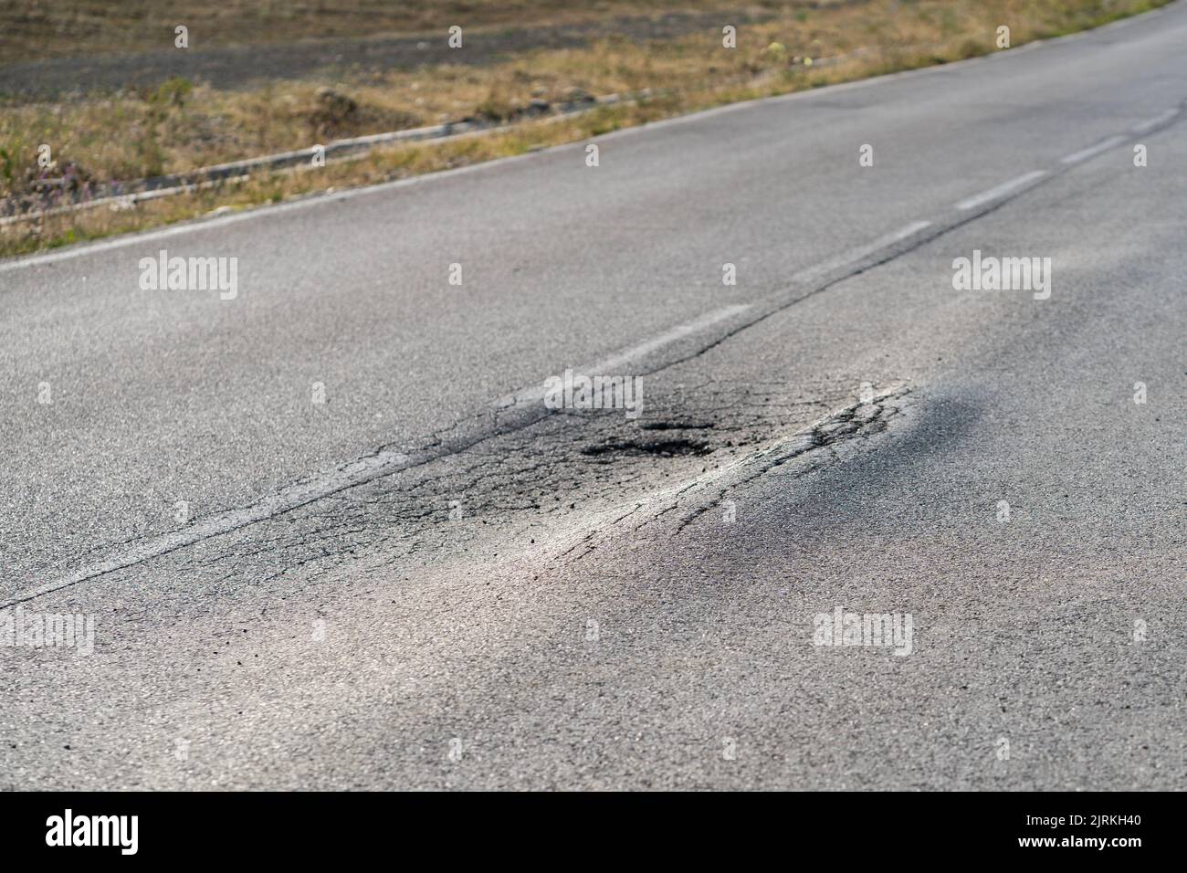 Deformed Asphalt Surface With Potholes Caused By Heavy Overloaded Trucks Driving On Highway
