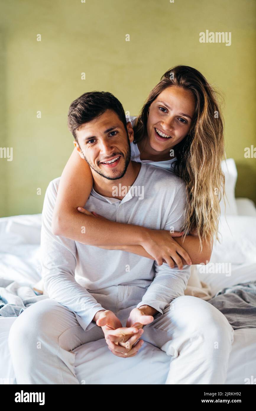 Smiling young girlfriend with long hair hugging gently happy boyfriend ...