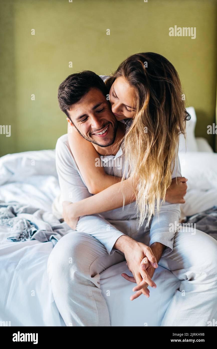 Smiling young girlfriend with long hair hugging gently happy boyfriend ...