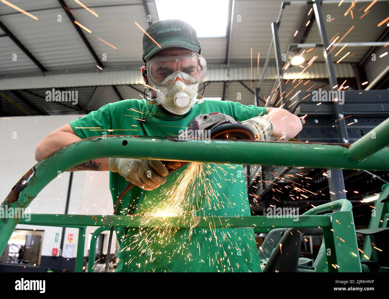Worker using an angle grinder. Cap, protective eyewear, mask and sparks ...