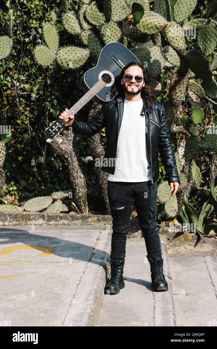 Bearded cheerful Latin American male musician in trendy wear standing ...