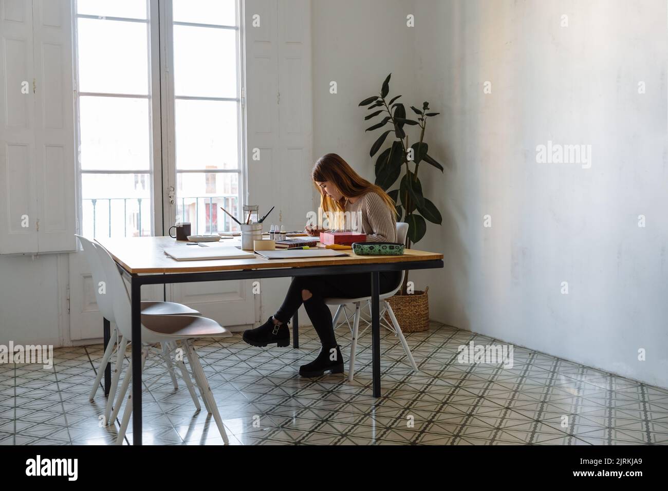 Young girl painting with watercolors in the interior of her house next ...