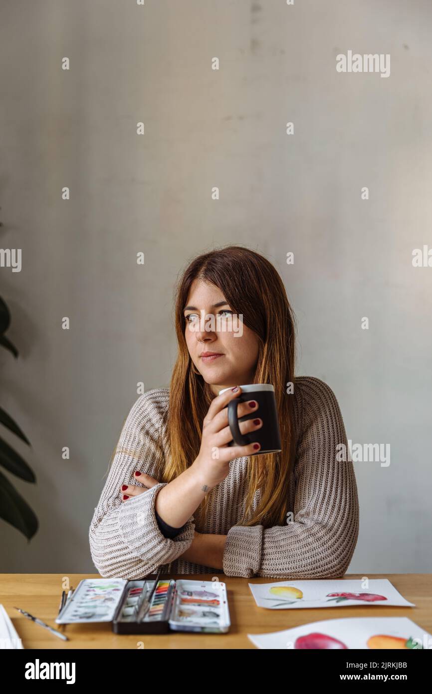 Artist having a cup of coffee with his drawings Stock Photo - Alamy