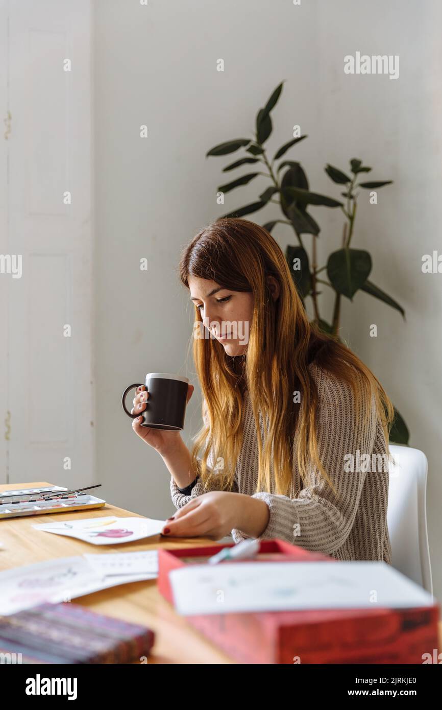 Artist having a cup of coffee with his drawings Stock Photo - Alamy