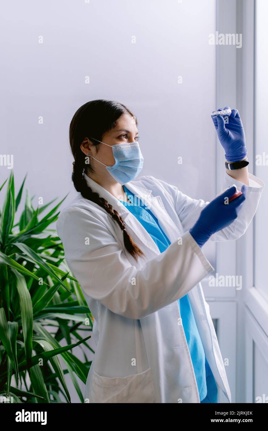 Side view of young female orthodontist in sterile mask and latex gloves ...