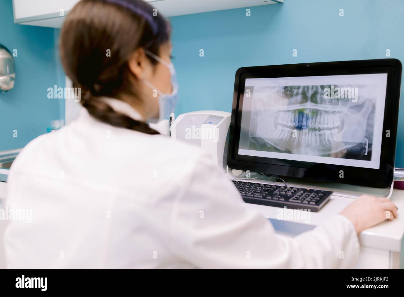 Back view of anonymous female orthodontist in mask against radiographic ...