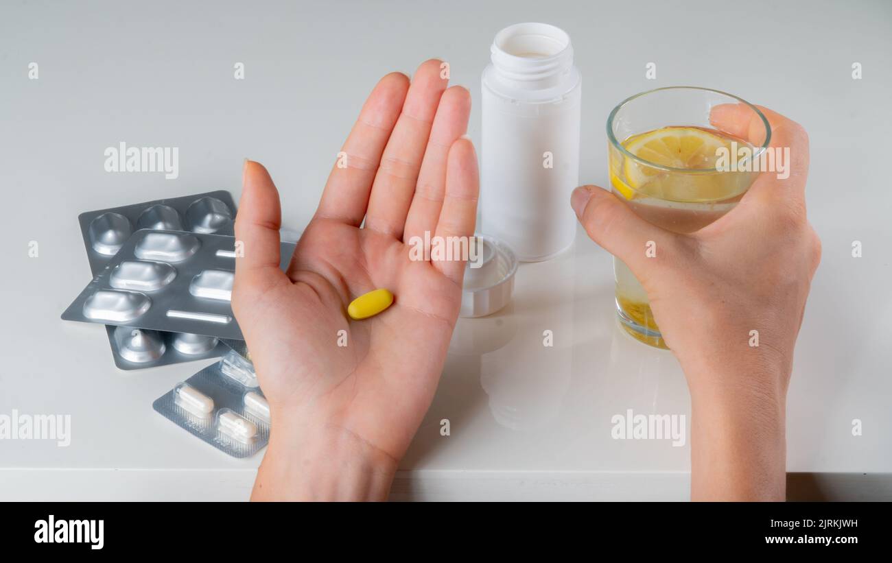 Pill tablet and a glass of water and lemon in your hands against the ...