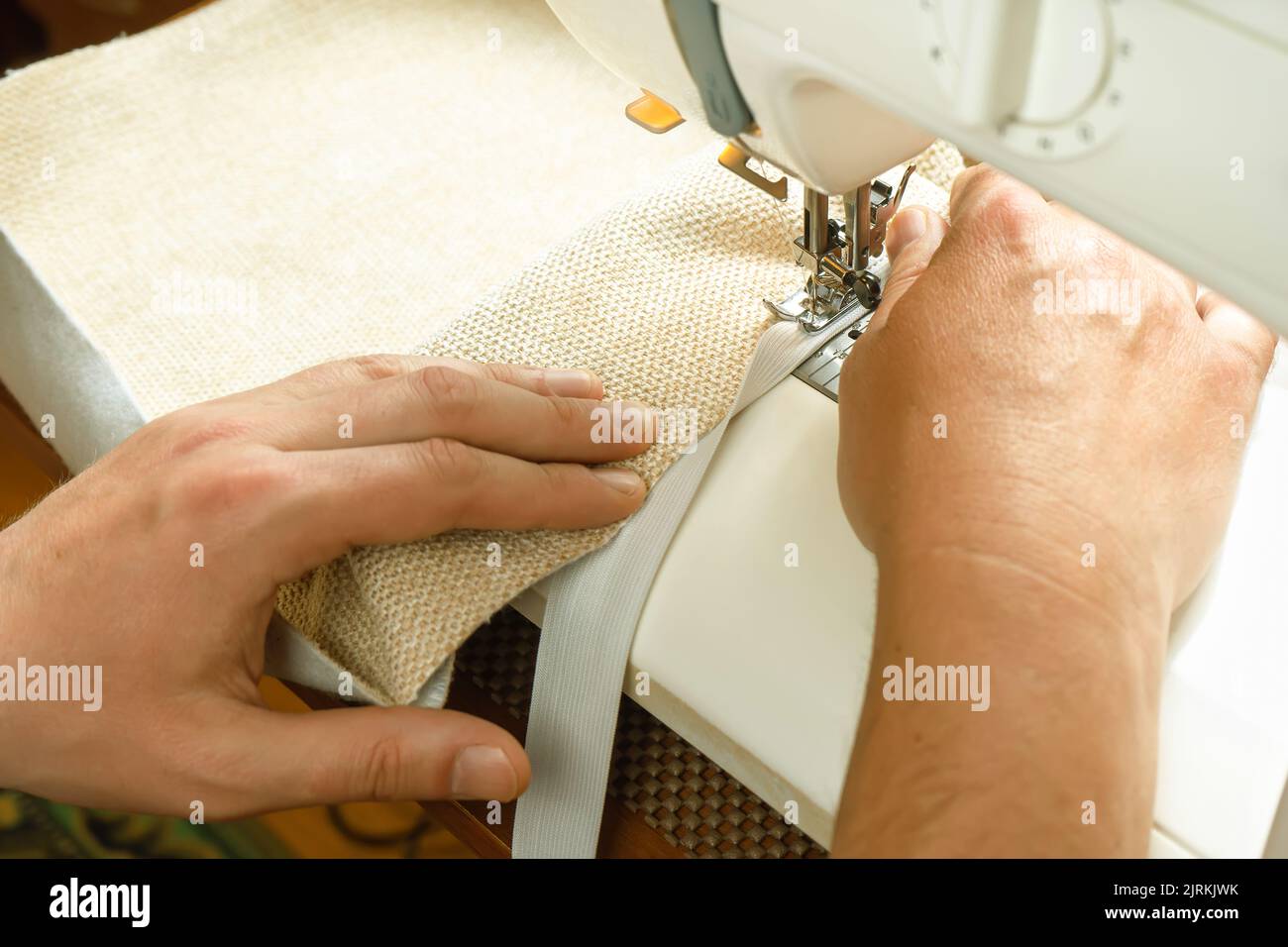 Seamstress hands holding white textile fabric. Male hands stitching ...